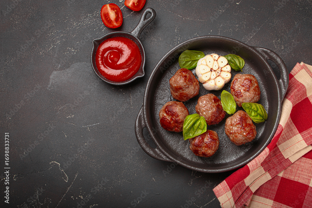Fried meatballs in a cast iron pan, surrounded by basil, aromatic ...