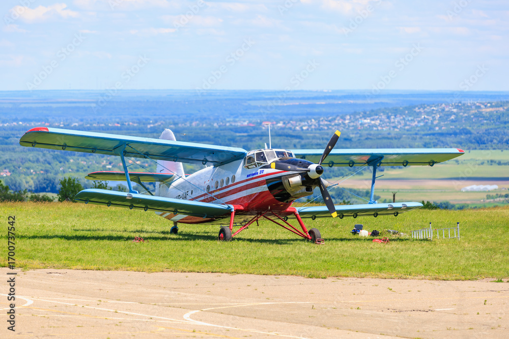 Vintage biplane on grassy airfield with scenic horizon in background ...