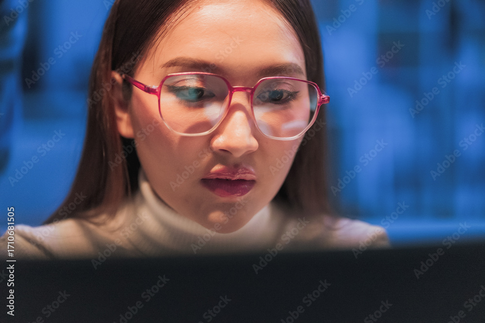 Asian programmer with glasses works late night shift in modern office ...