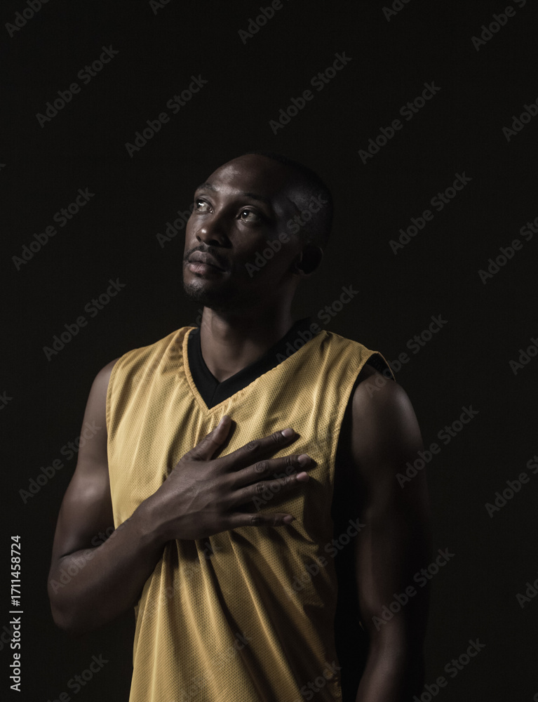 Basketball player in yellow jersey looking up, hand on chest ...