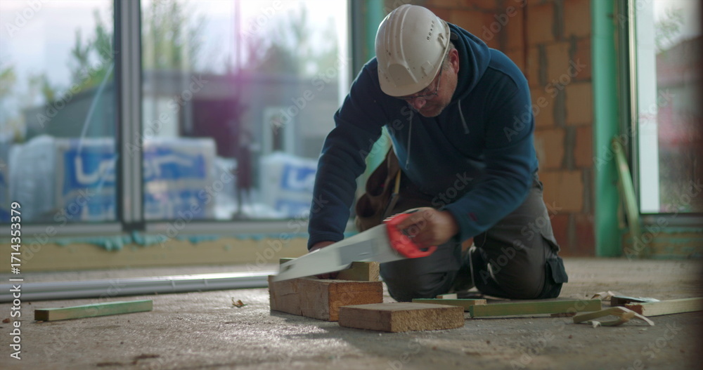 Construction worker sawing wood on indoor construction site ...