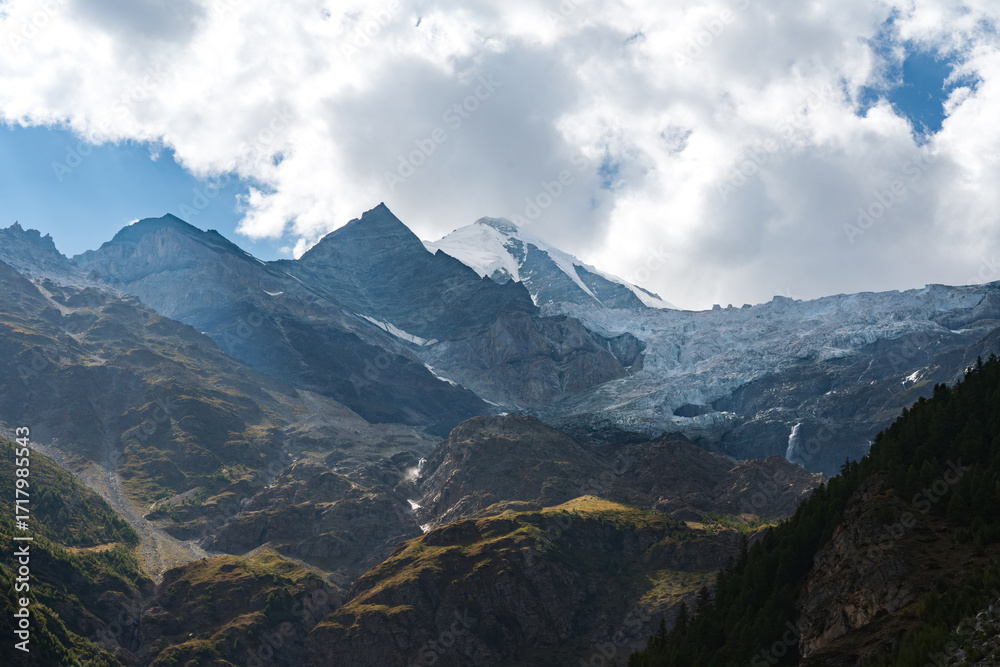 Snow-capped Swiss Alps mountains with a glacial waterfall and flowing ...