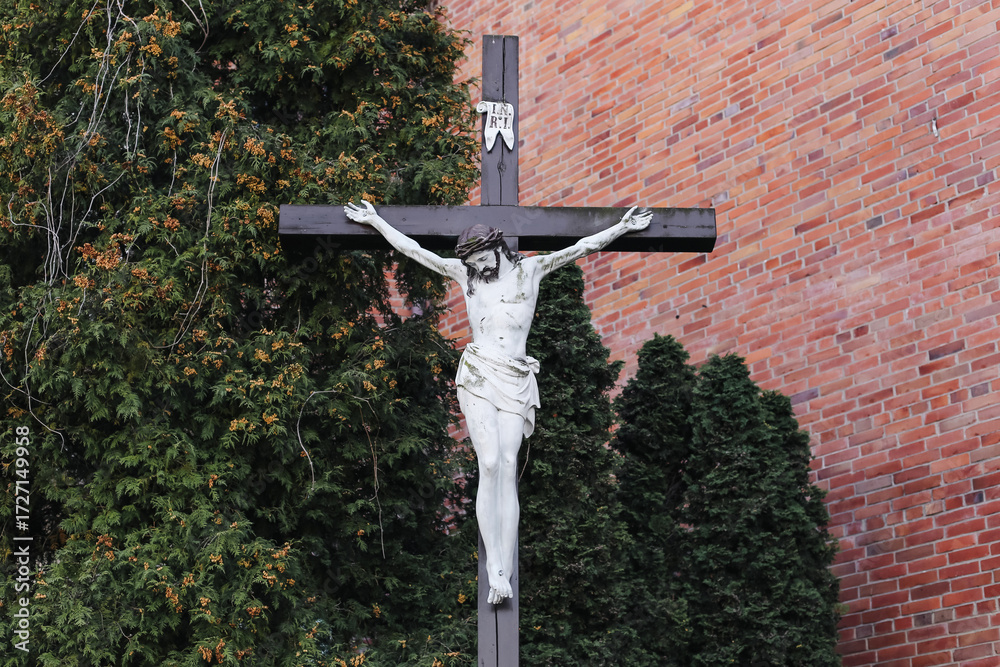 Religious crucifix monument. Jesus on cross statue in front of brick ...
