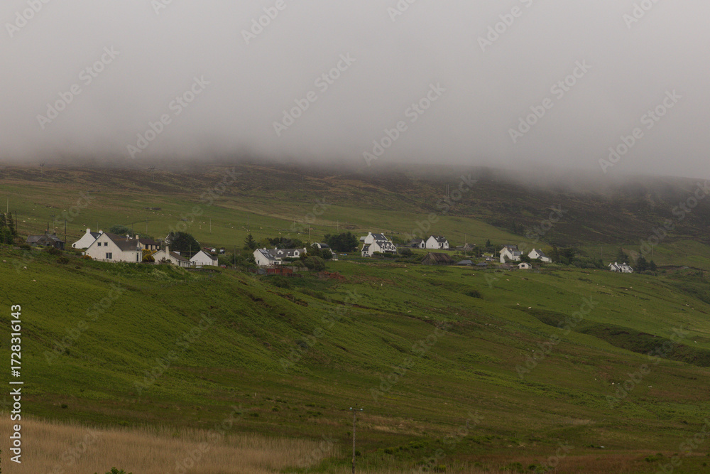 Row of traditional scottish cottages embedded in rain clouds in Stein ...