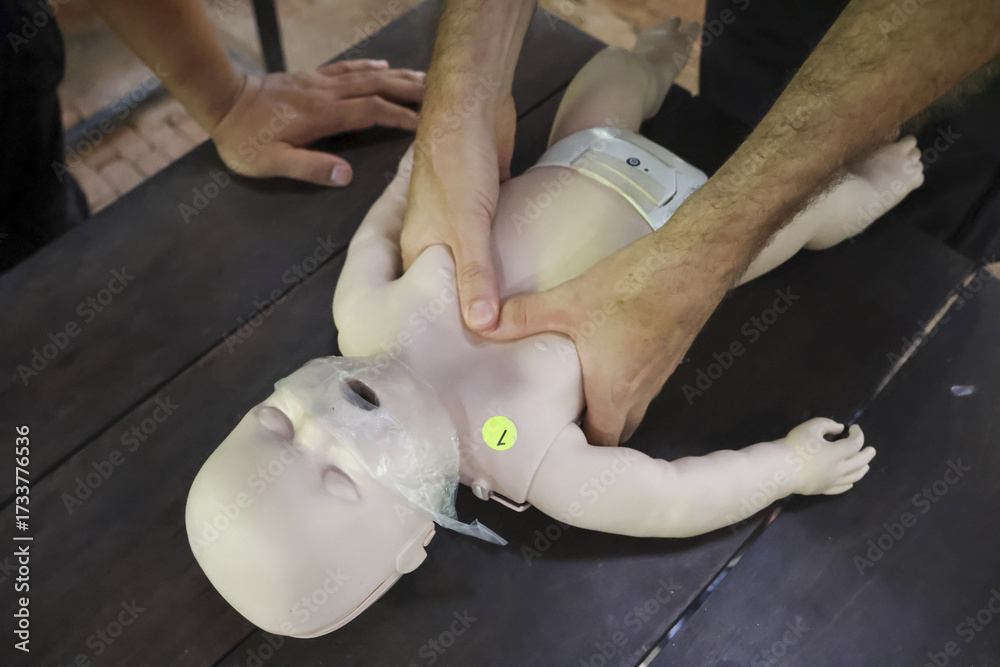 Medical training dummy simulates infant CPR procedure, showing hands ...