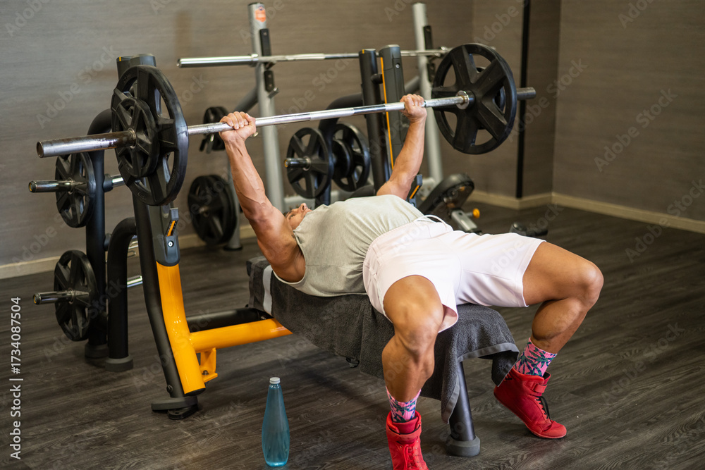 Muscular man performing a bench press exercise at the gym ...