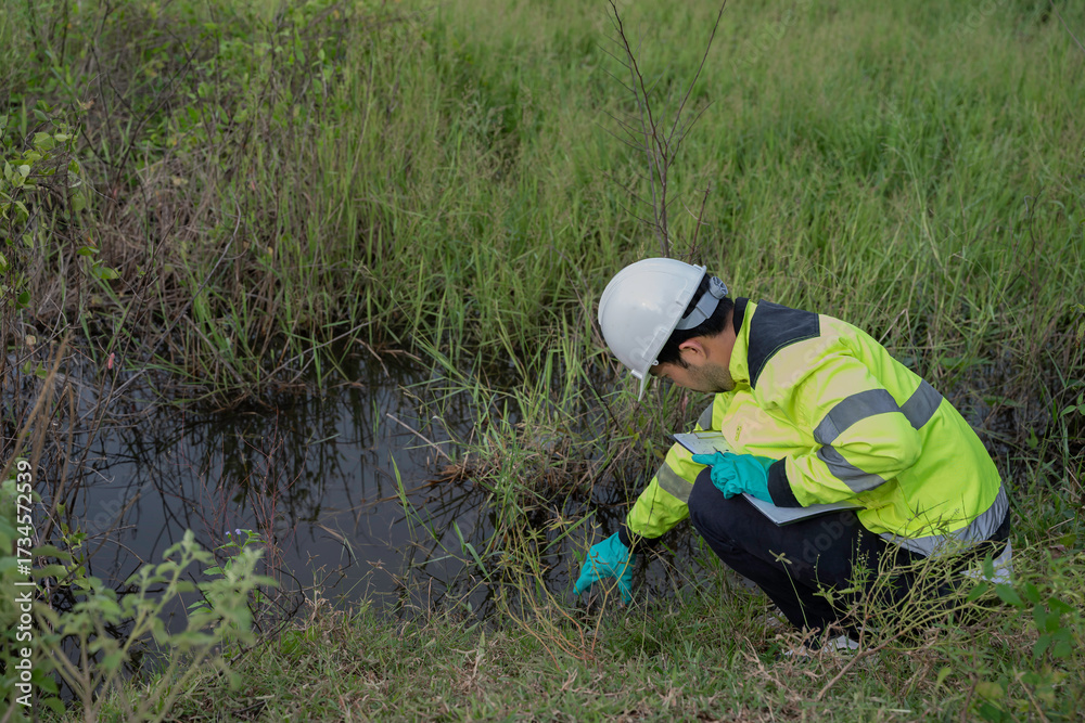 Environmental engineer wearing safety gear collecting water sample from ...