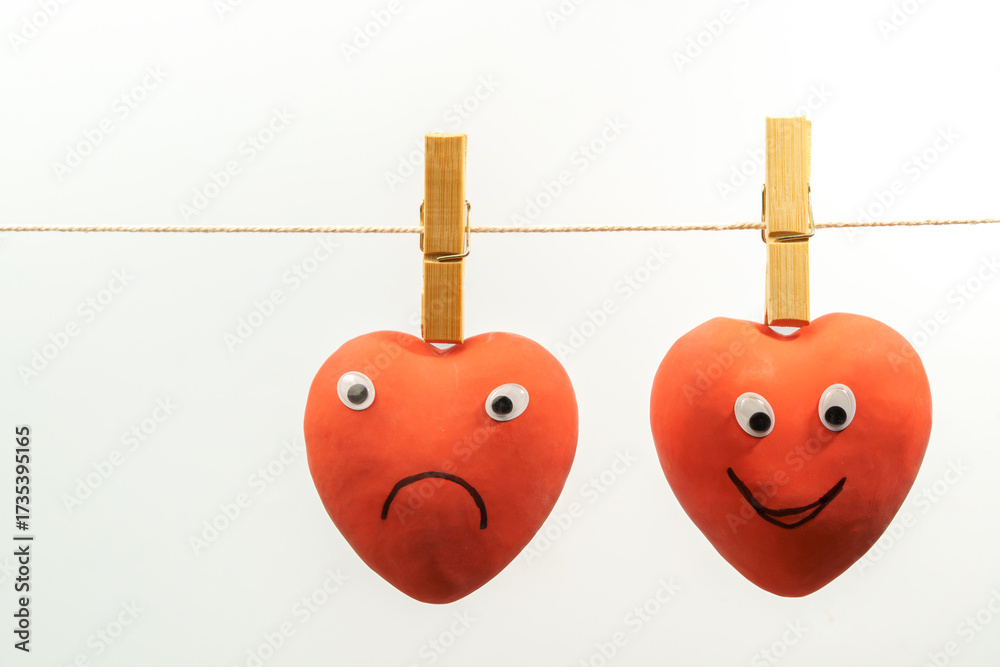 Hearts with happy and sad expressions hanging on a rope, representing ...