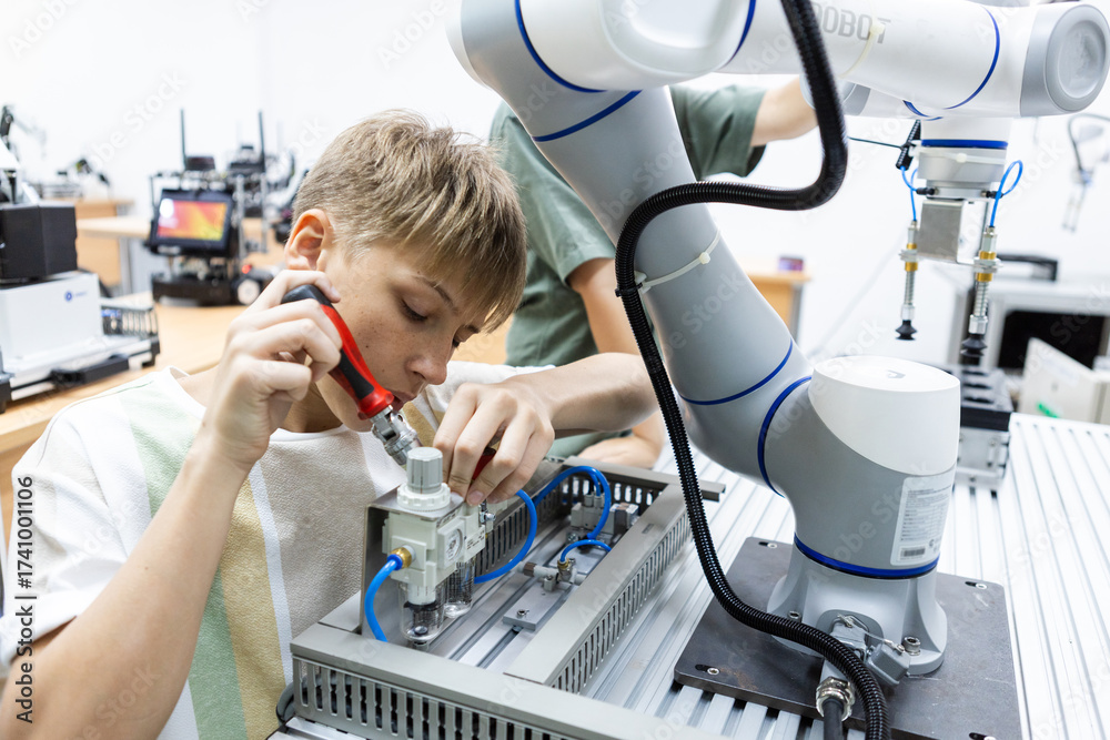 Young student assembling robotic arm in a lab environment. Concept of ...
