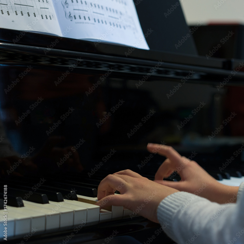 Human hands playing the keys notes and chords on a classic black piano ...