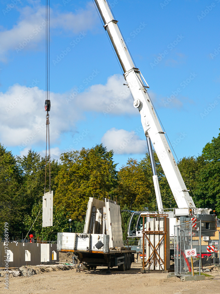 Crane lifting precast wall panel at residential building construction ...