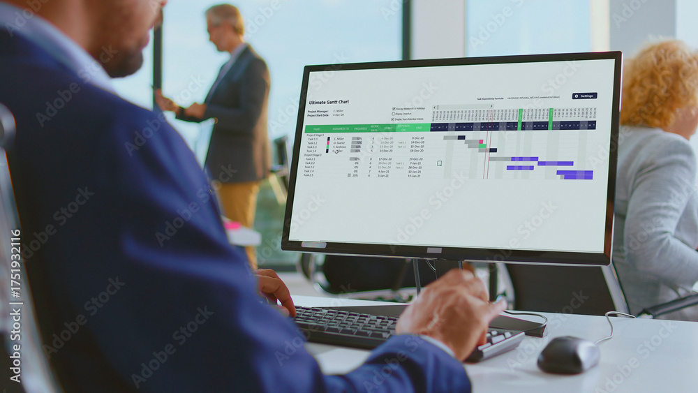 Project manager analyzing a gantt chart on a desktop monitor, planning ...