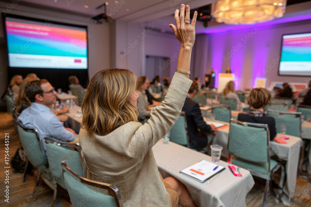 Businesswoman raising hand in modern conference room during corporate ...