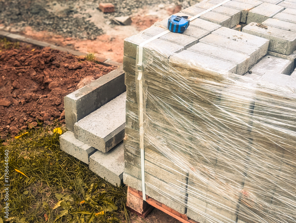 pallet of wrapped concrete paver blocks on a construction site with ...