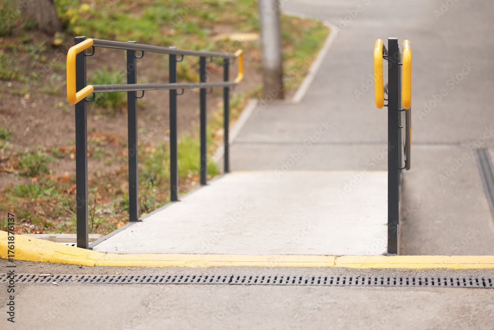 Accessibility ramp with yellow handrails and smooth concrete surface ...