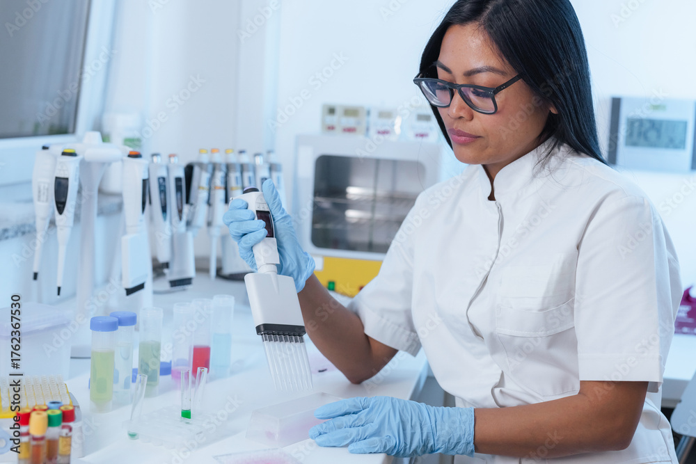 Female laboratory technician pouring reagent with a multi-channel ...
