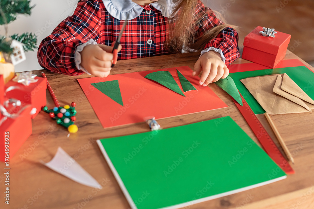 Child crafting christmas decorations at home with red and green paper ...