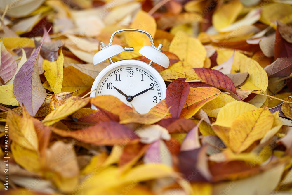 Classic white analog alarm clock partially covered in pile of yellow ...