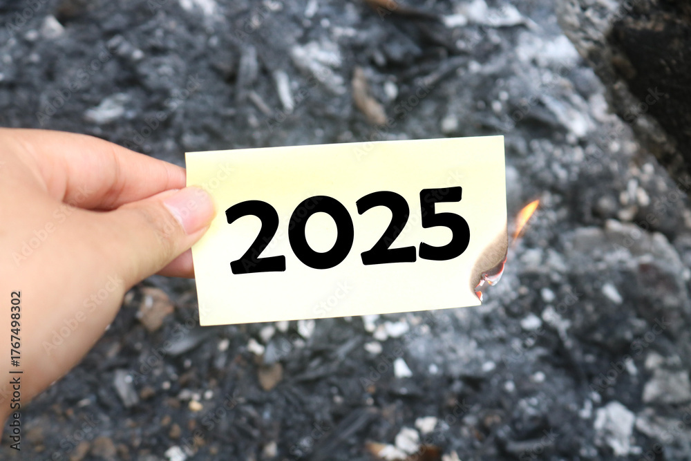 Hand holding a half-burnt note with 2025 written on it. Goodbye 2025 ...