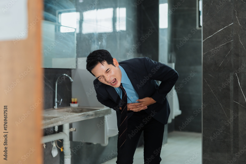 Asian businessman feeling immense abdomen pain and discomfort in an ...