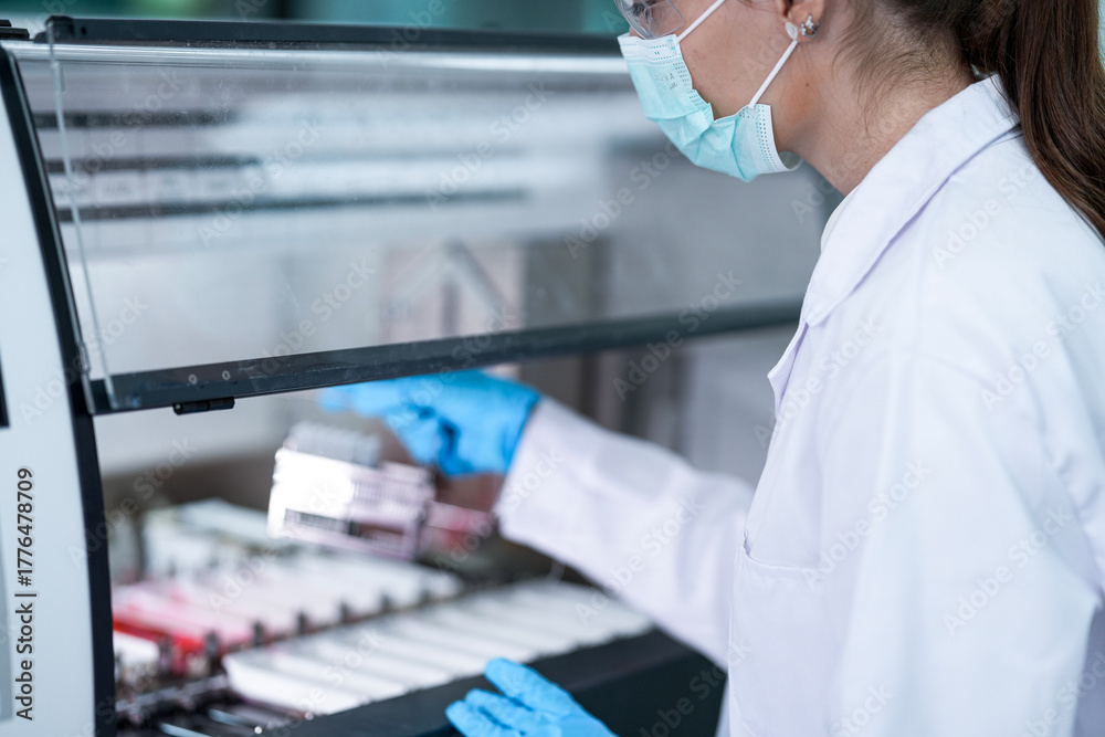 A clinical laboratory scientist loads a sample rack into a high ...