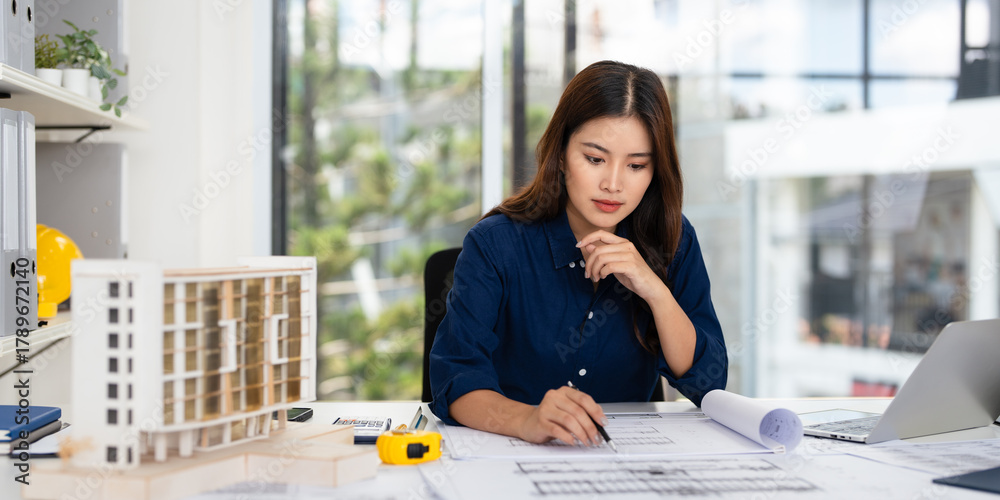 Young asian civil engineer studying a blueprint floor plan and working ...