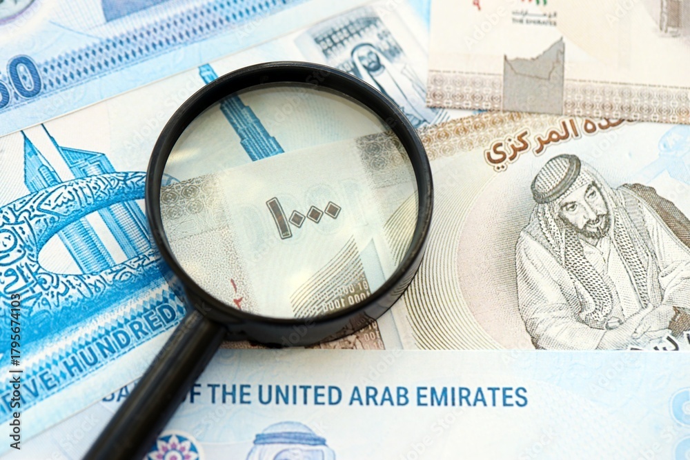 United Arab Emirates dirham currency money bills and magnifying glass ...