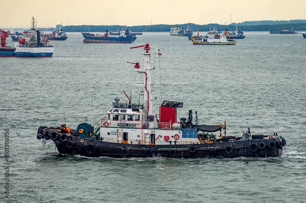 Tugboat navigates the madura strait, assisting larger vessels in the ...