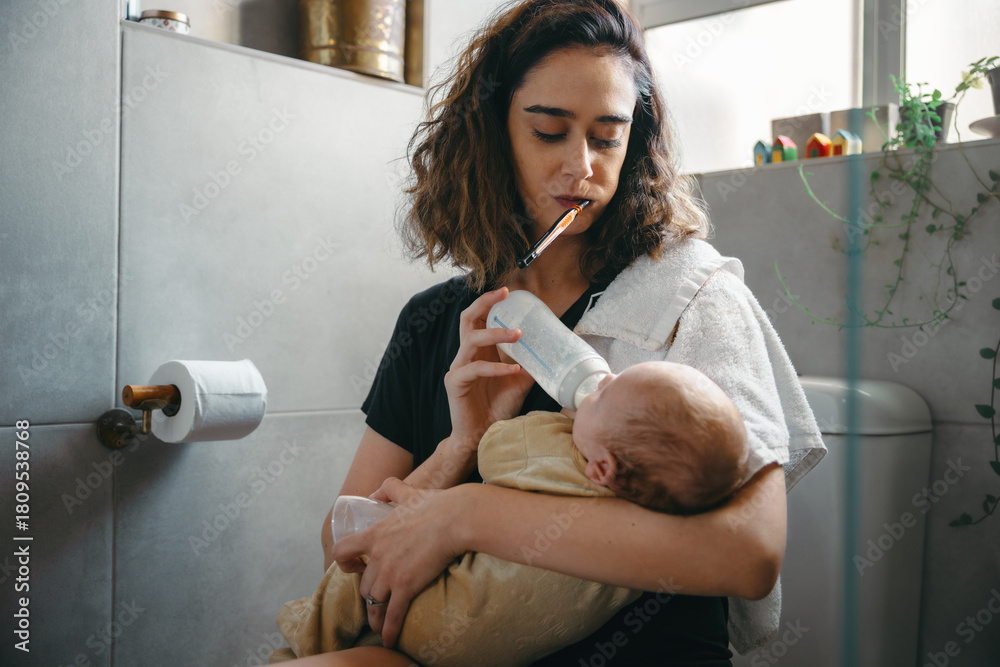 Mother multitasking in bathroom while feeding baby Stock Photo | Adobe ...