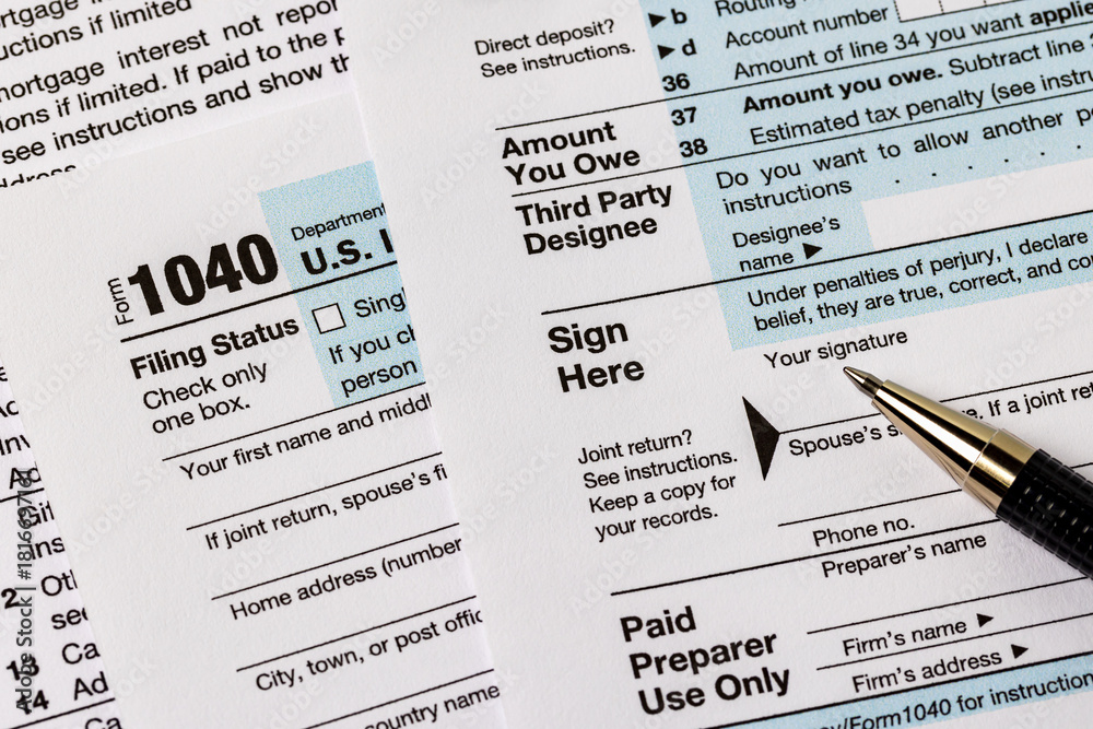 Signing 1040 federal income tax form. Tax preparation, fraud, and ...