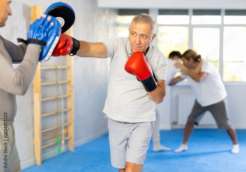 Coach and mature man pupil are engaged during training, boxing classes ...