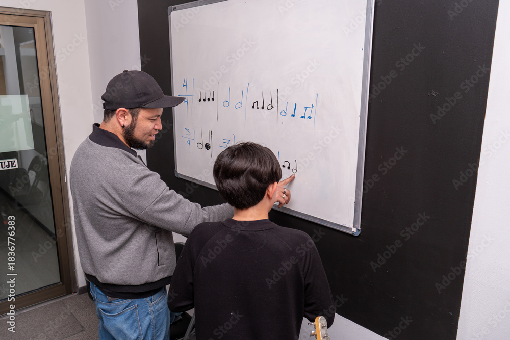 Student practices rhythm writing on the board while the teacher offers ...
