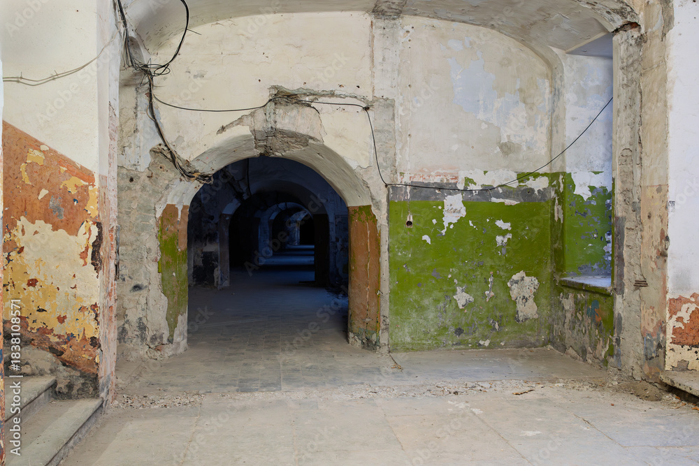 Abandoned prison corridor with arched tunnel entrance and peeling green ...