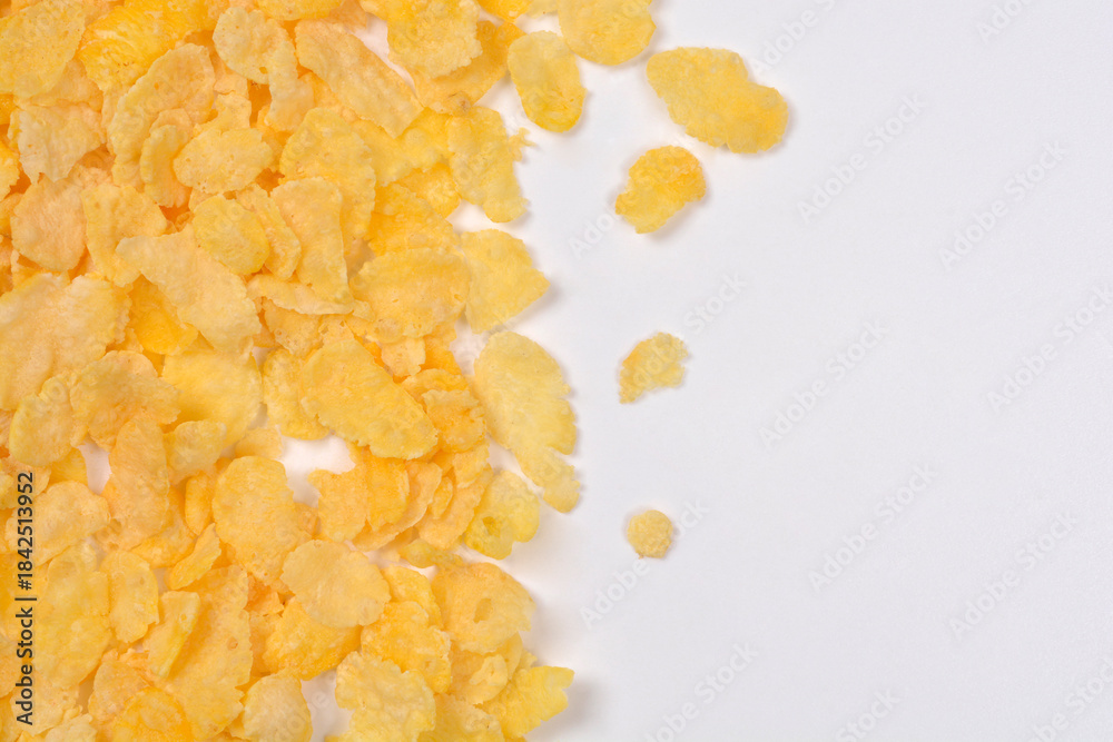 Golden corn flakes fill the left side of the frame, leaving a large ...