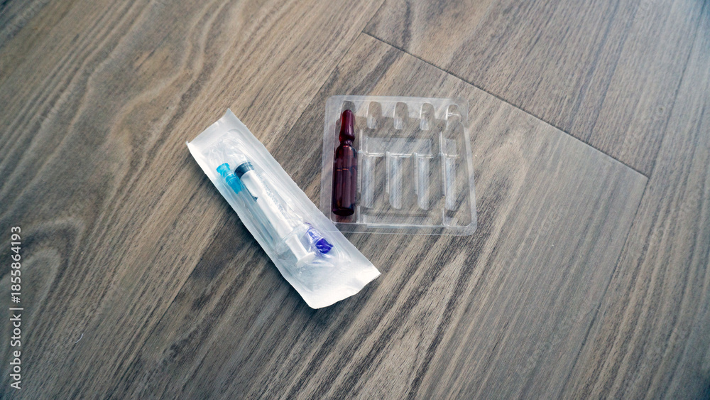Medical syringe in transparent plastic packaging and red liquid ...