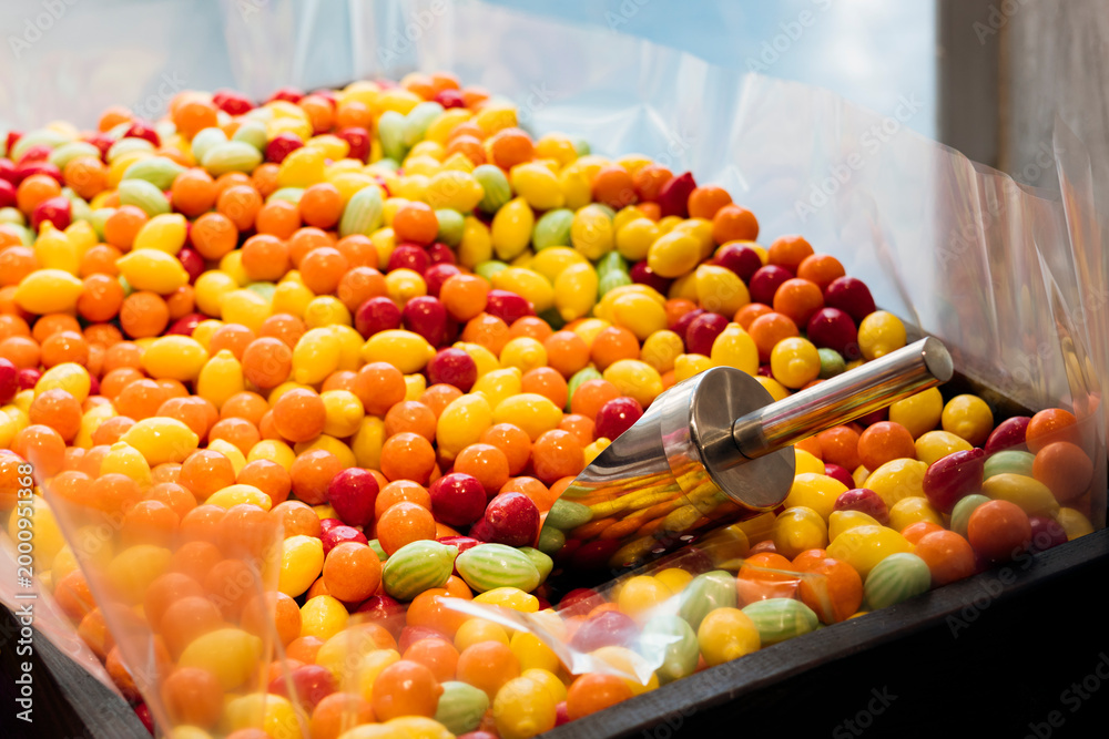 Assorted fruit shaped gummy candies and chewy gum in a container ...