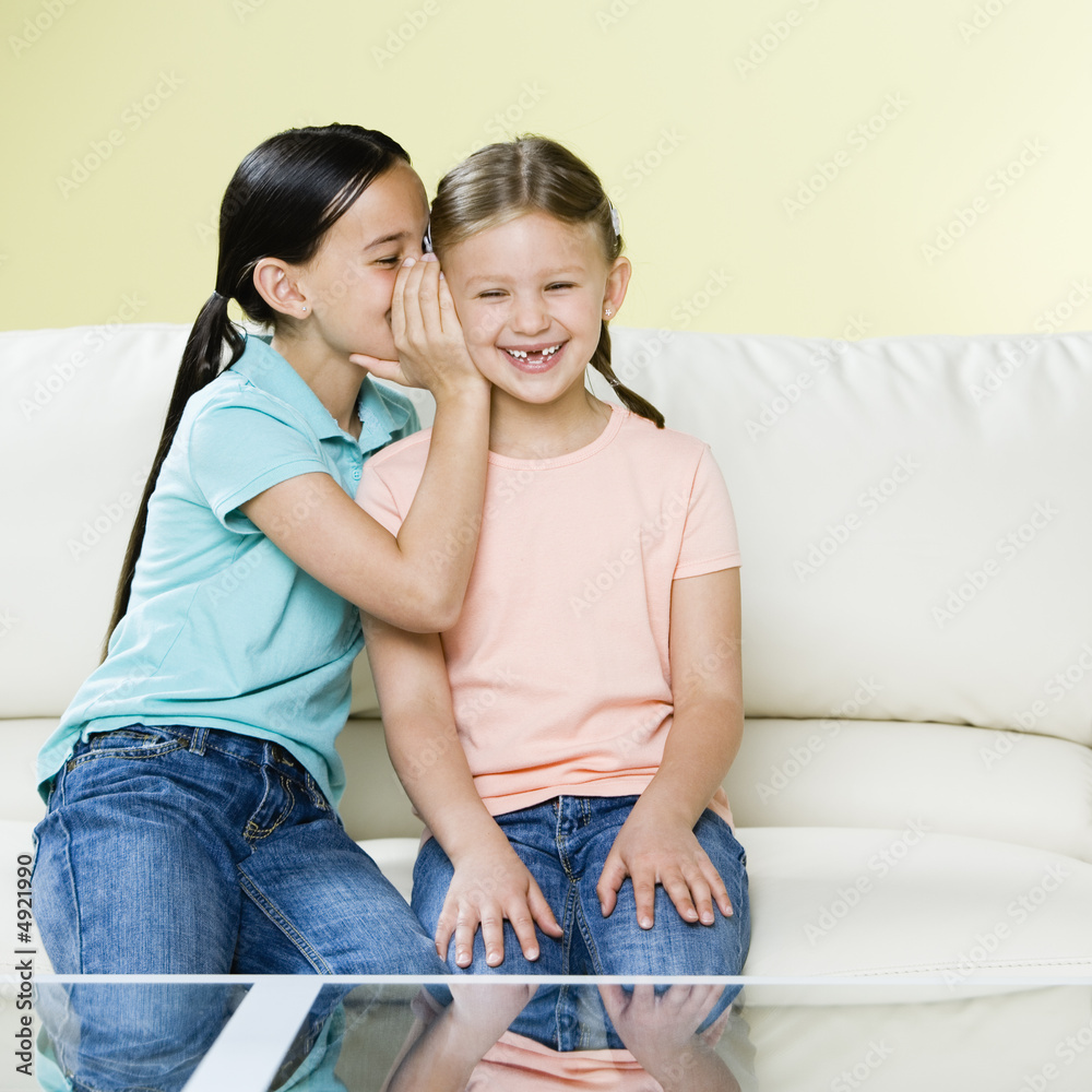 Two girls telling secret on couch Stock-Foto | Adobe Stock