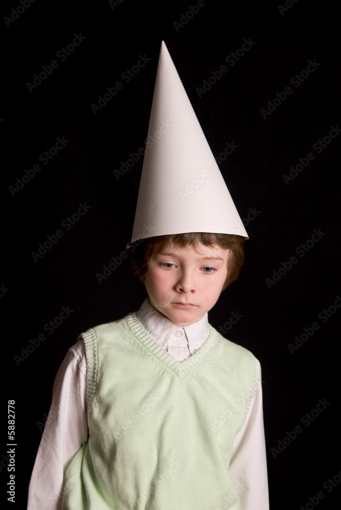 Sad young boy in a dunce cap over a black background Stock Photo ...