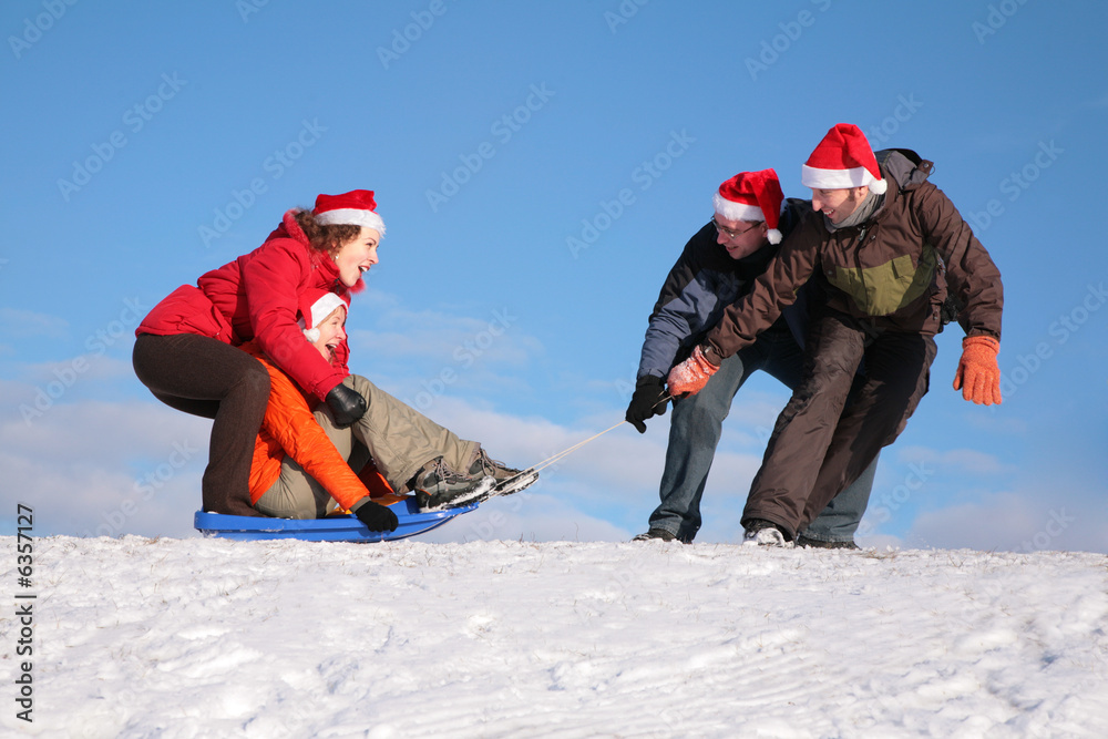 two men pull two women on sled Stock Photo | Adobe Stock