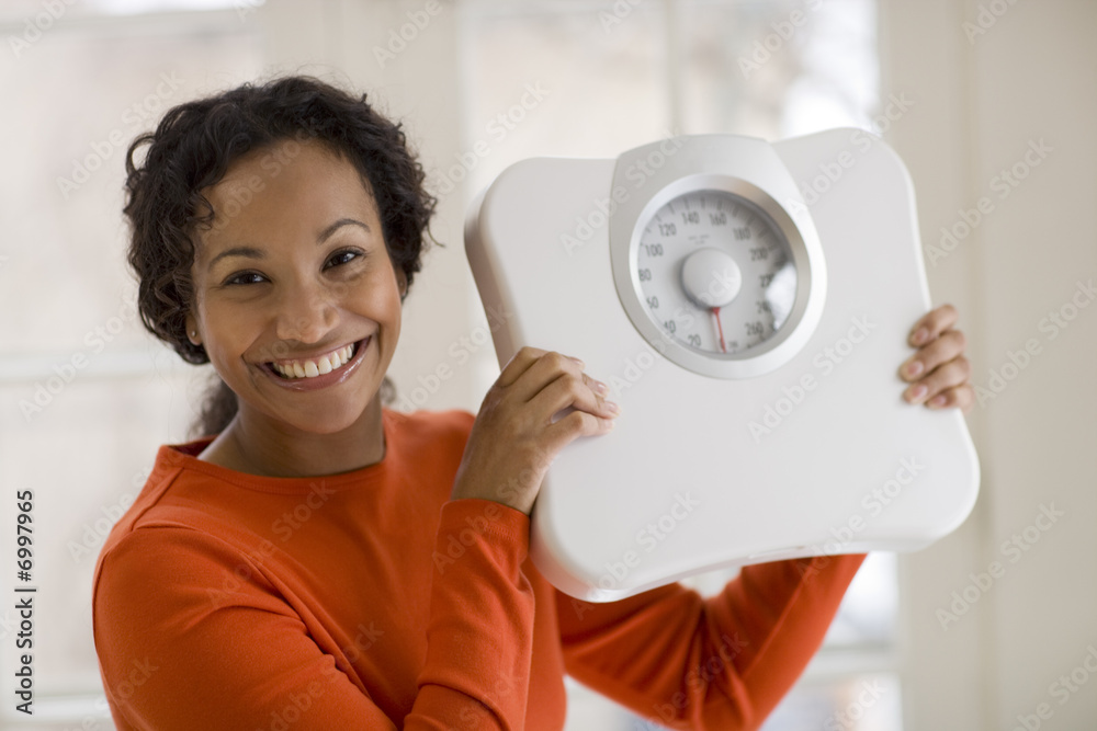 Happy Black woman holding scale Stock Photo | Adobe Stock