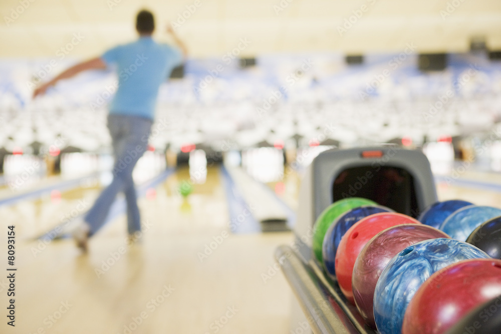 Bowling ball machine with man bowling in the background Stock Photo ...