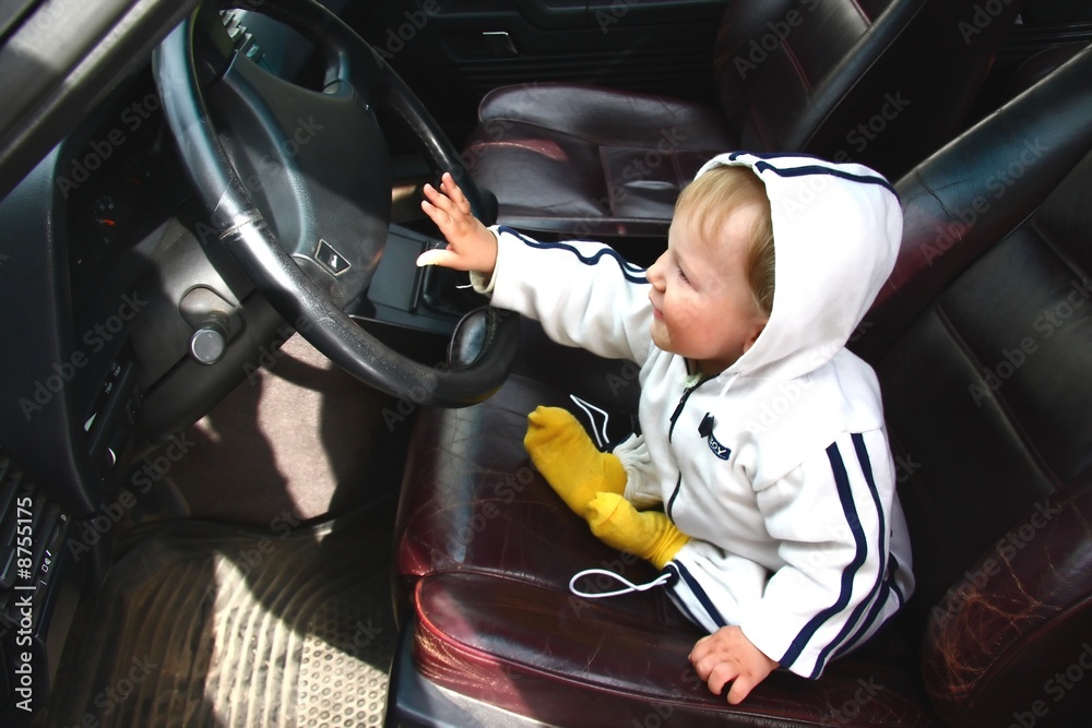 child sits behind the steering wheel of a car Stock Photo | Adobe Stock