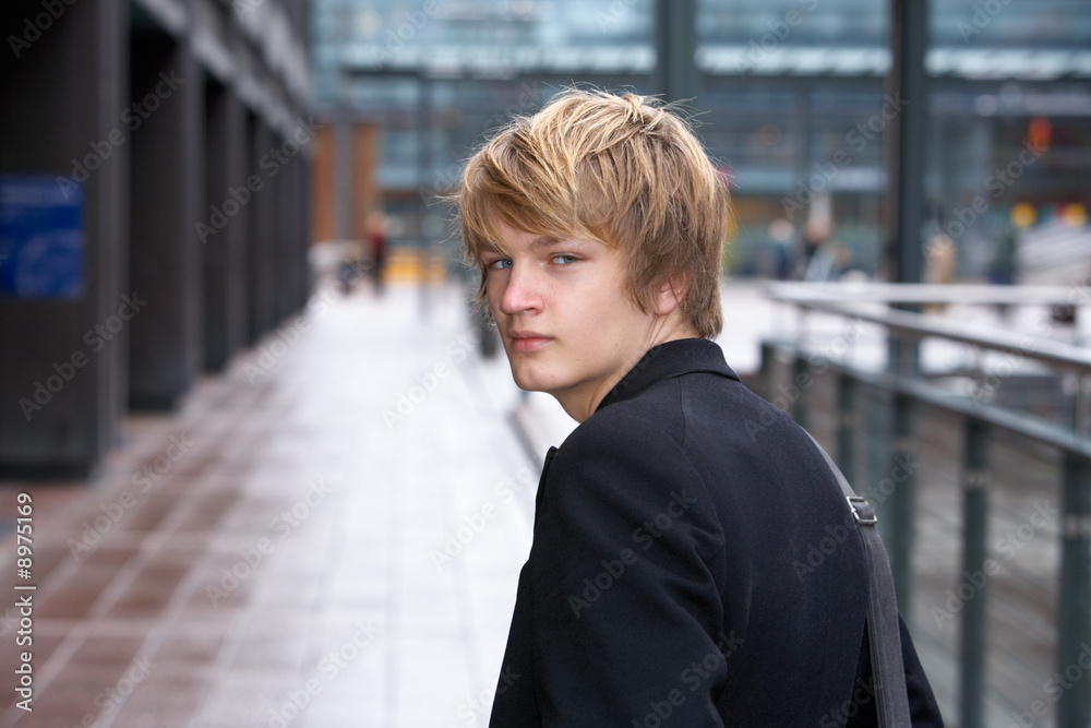 Teenage boy looking back over his shoulder in city Stock Photo | Adobe ...