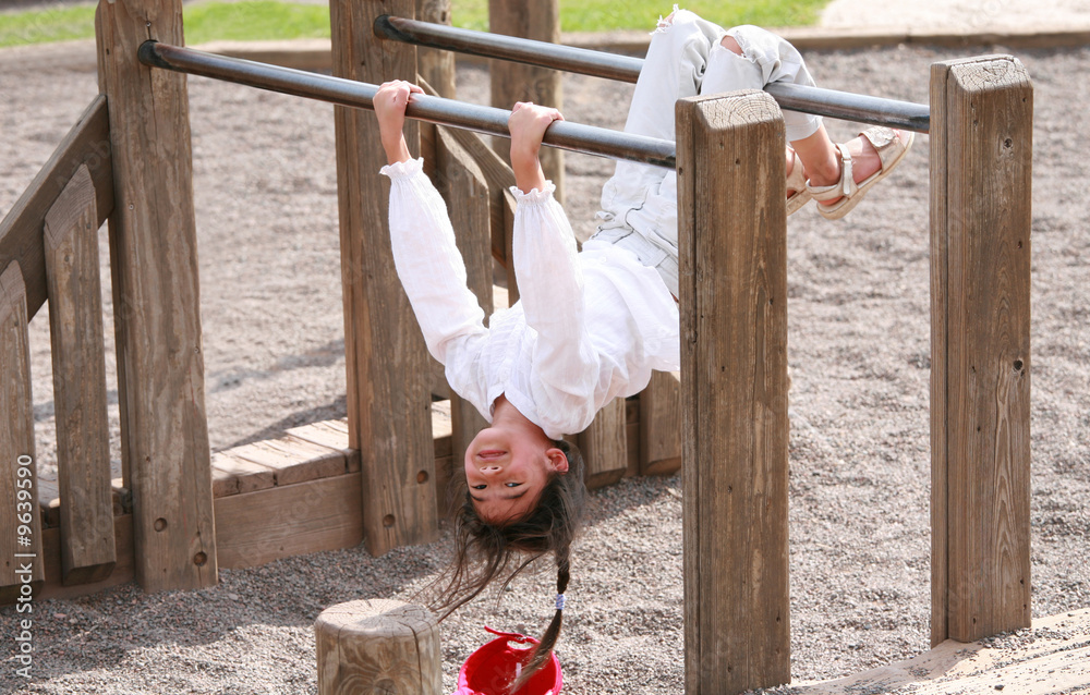 Little girl hanging upside down on parallel bars at playground Stock ...