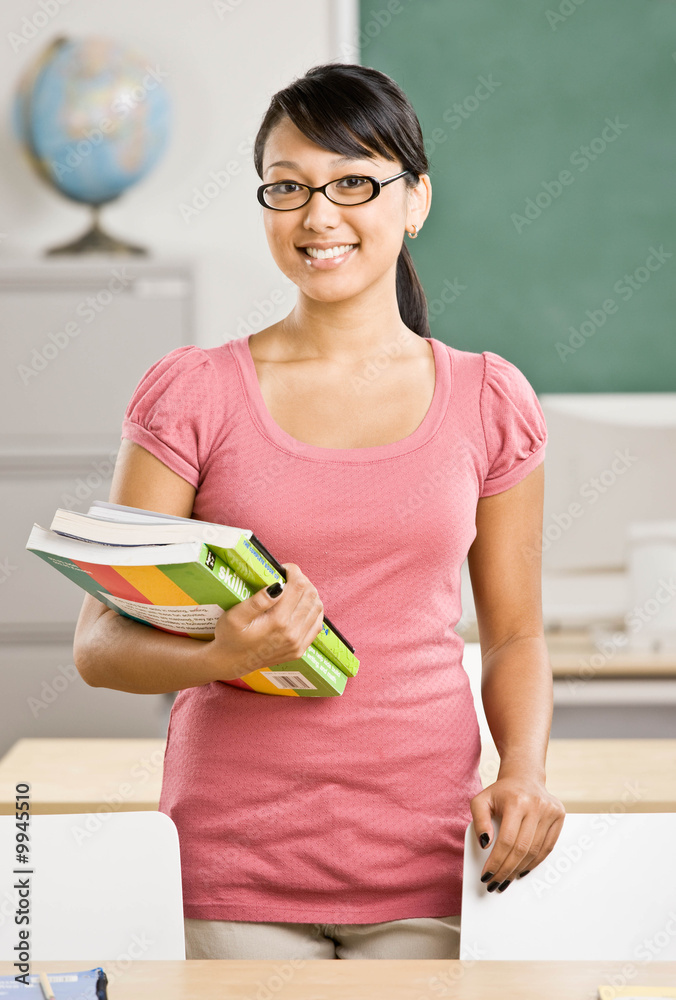 Happy teacher holding text books in school classroom Stock Photo ...