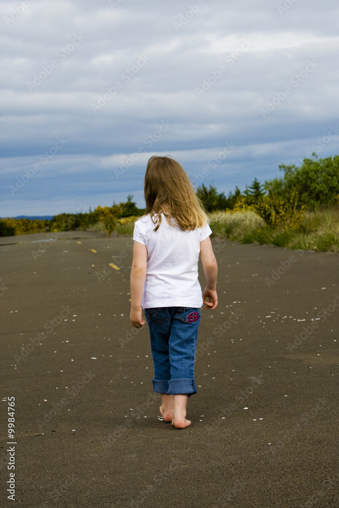 Young child walking alone down empty road Stock Photo | Adobe Stock