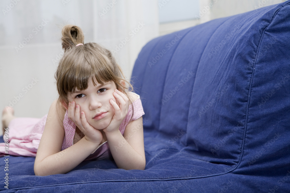 cute sceptical little girl lying on sofa Stock Photo | Adobe Stock