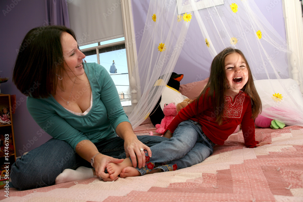 mother tickling her little girl's bare feet on the bed Stock Photo ...