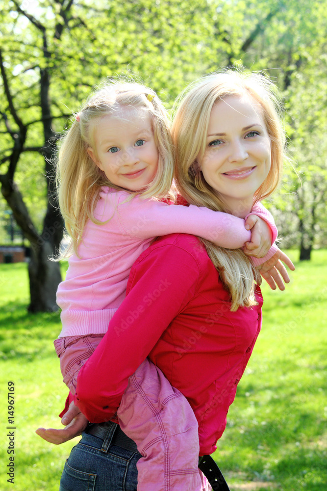daughter sits at mother on back in spring park Stock Photo | Adobe Stock