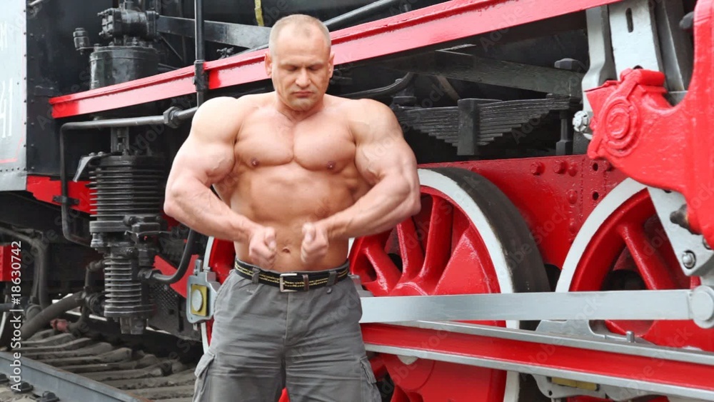shirtless bodybuilder stands on railroad against locomotive Stock Video ...